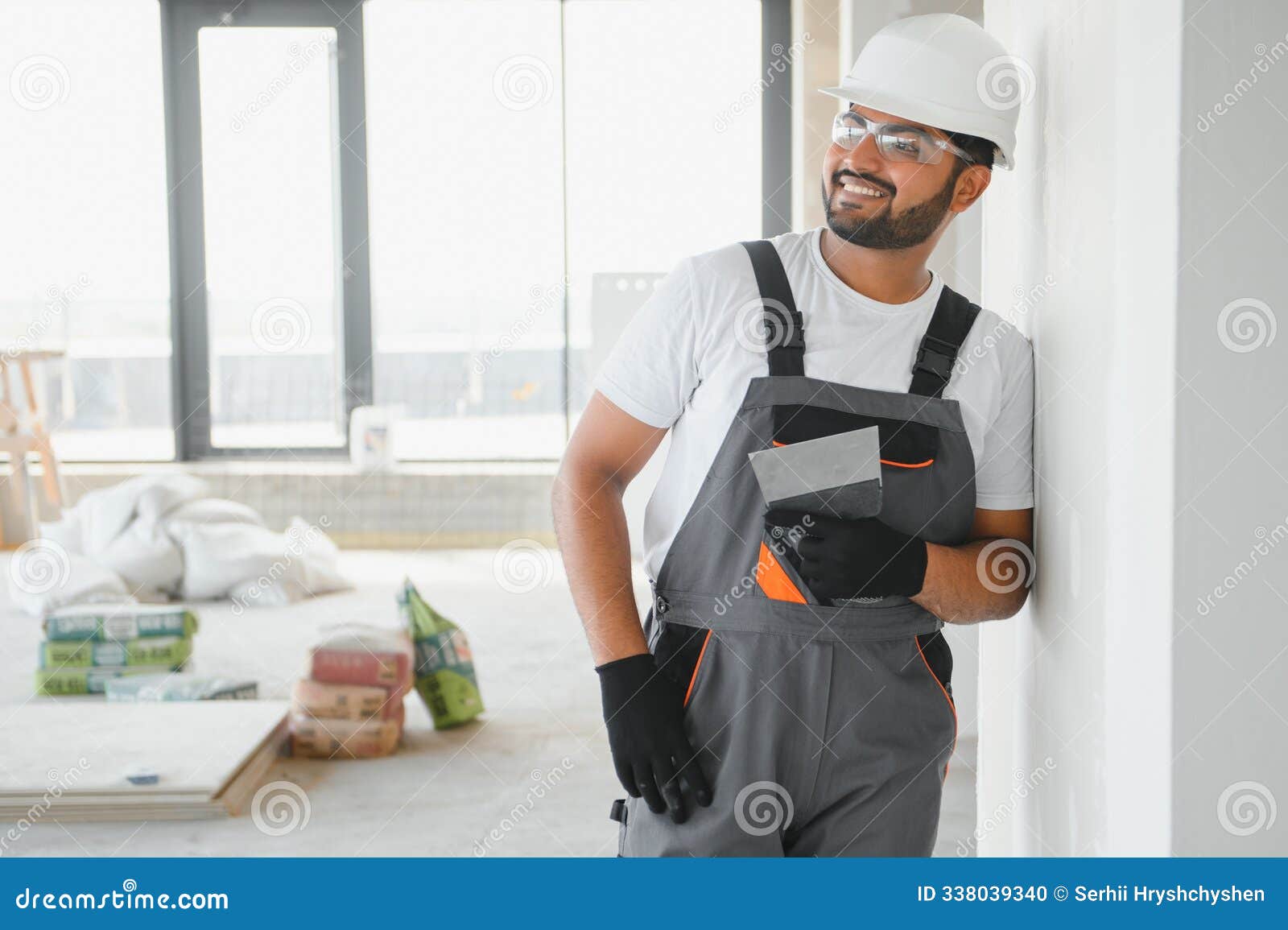 Indian Male Builder in Work Overalls Plastering a Wall Using a ...