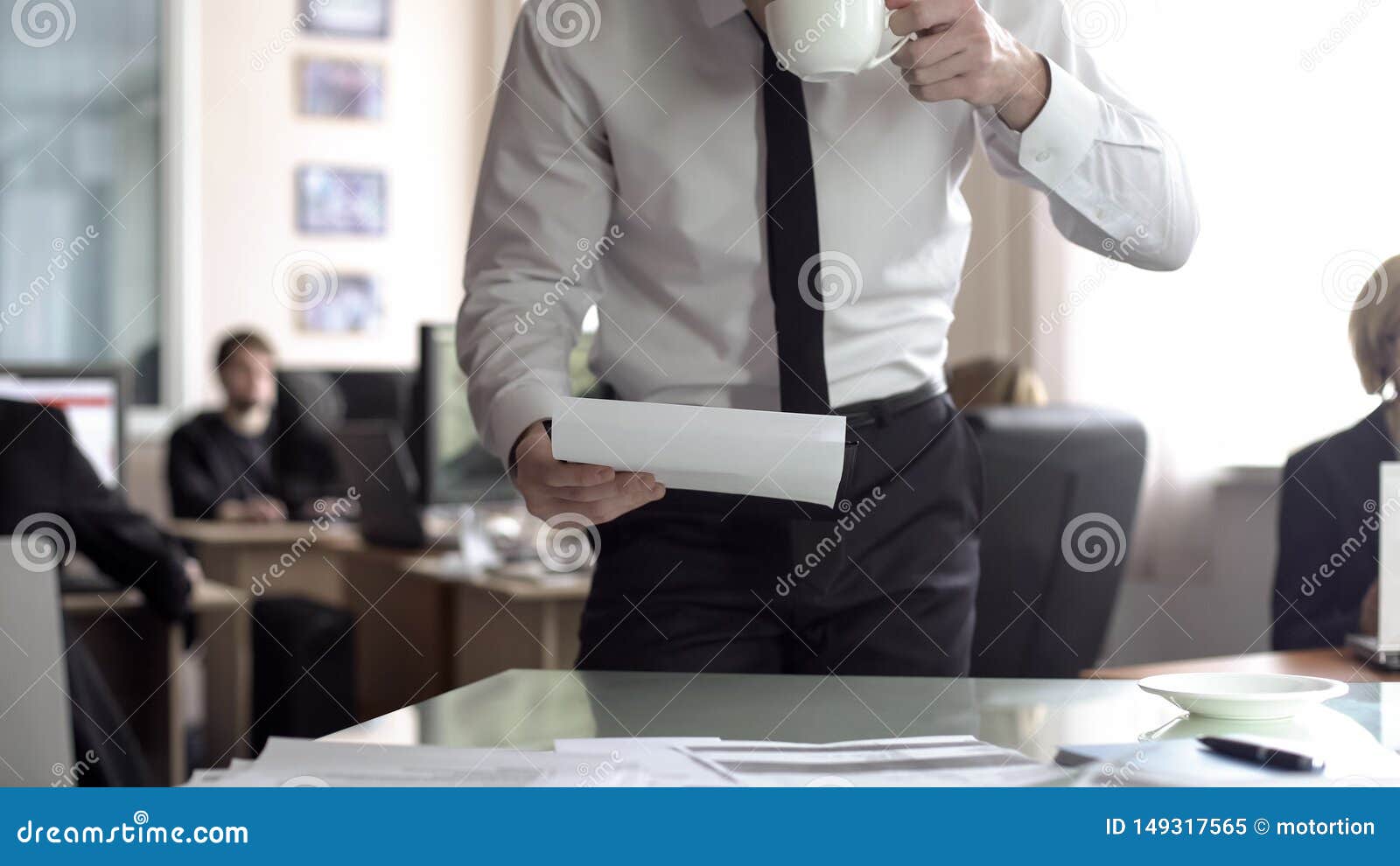 Male CEO Looking through Documentation and Drinking Tea, Standing in ...