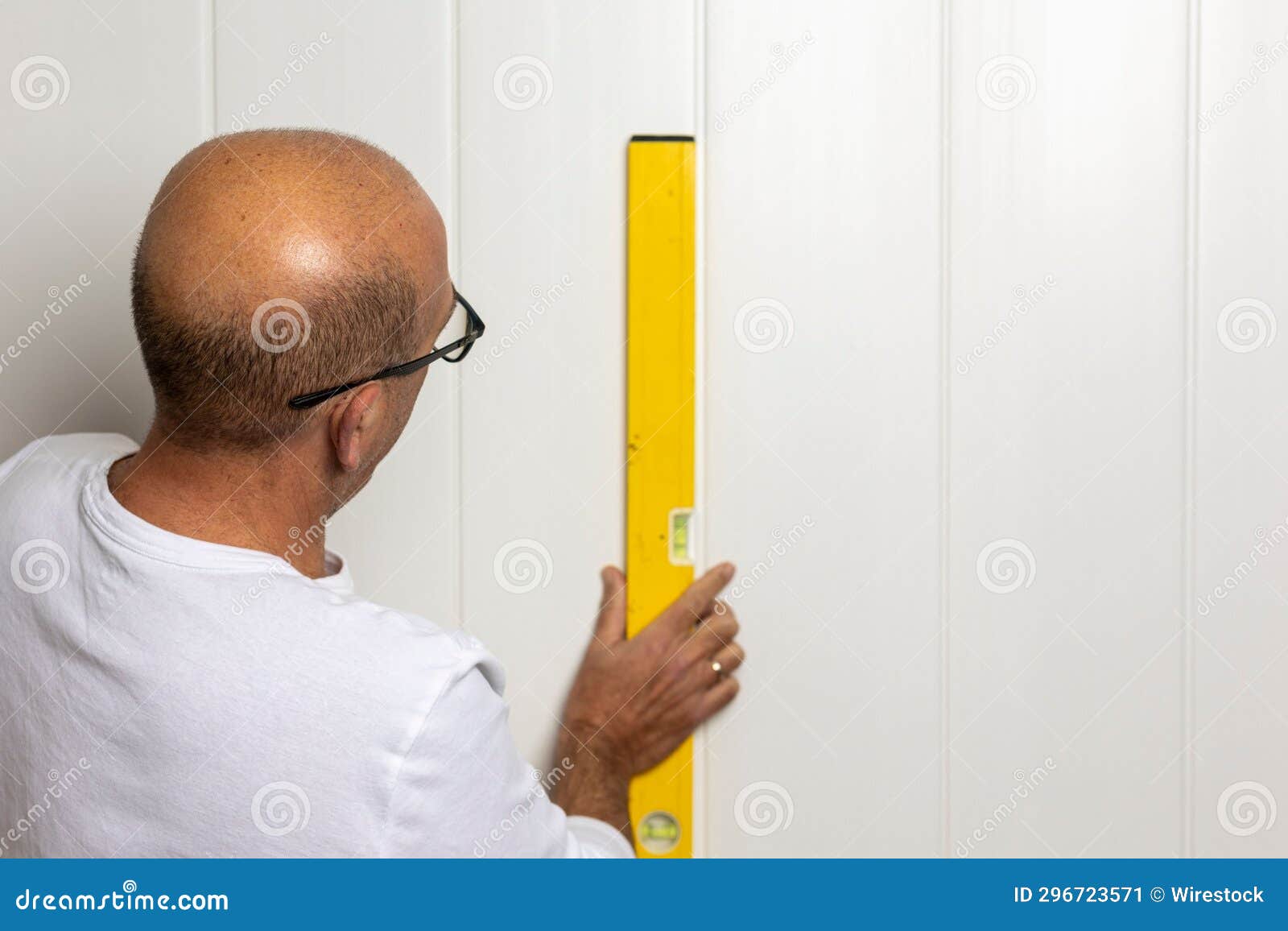 Male Construction Worker is Standing Near a Wall, Measuring the Length ...