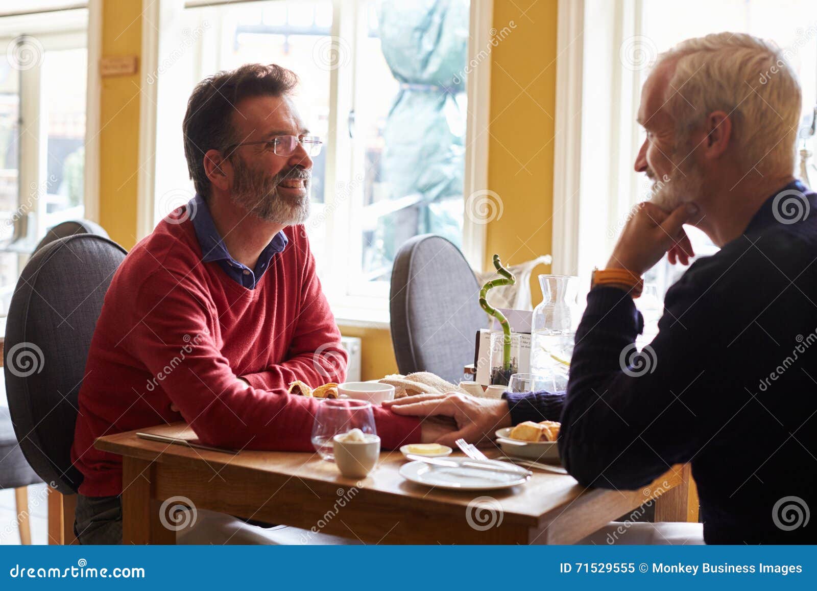 A Male Couple Holding Hands at a Restaurant Table, Side View Stock ...