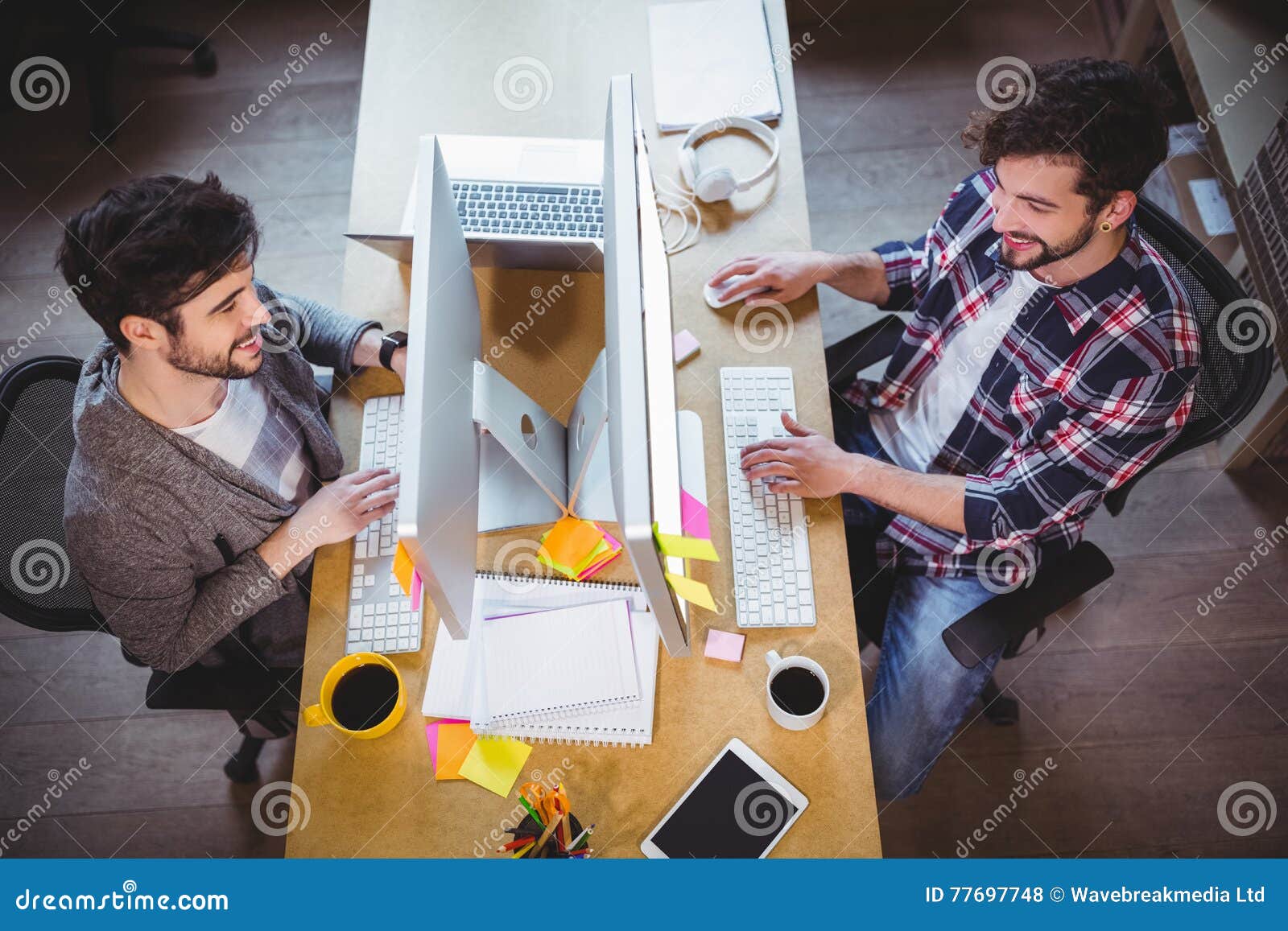 Male Coworkers Smiling while Working at Computer Desk Stock Photo ...