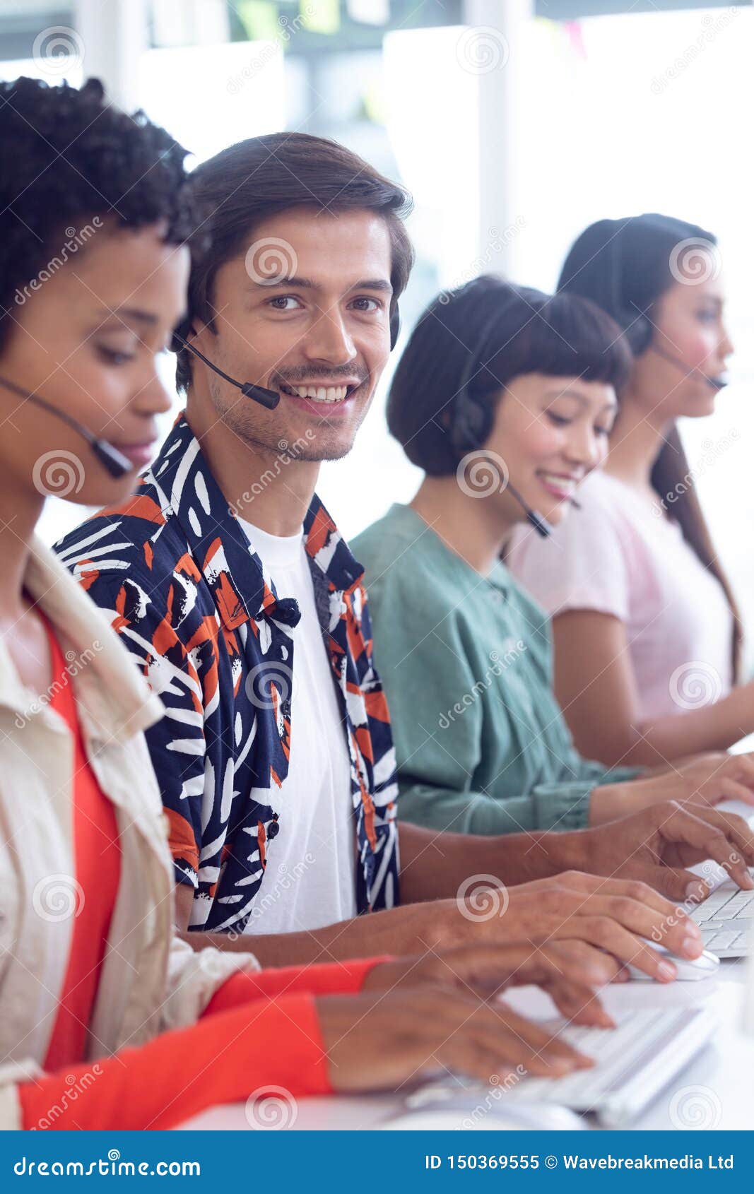 Male Customer Service Executive Working on Computer at Desk in Office ...