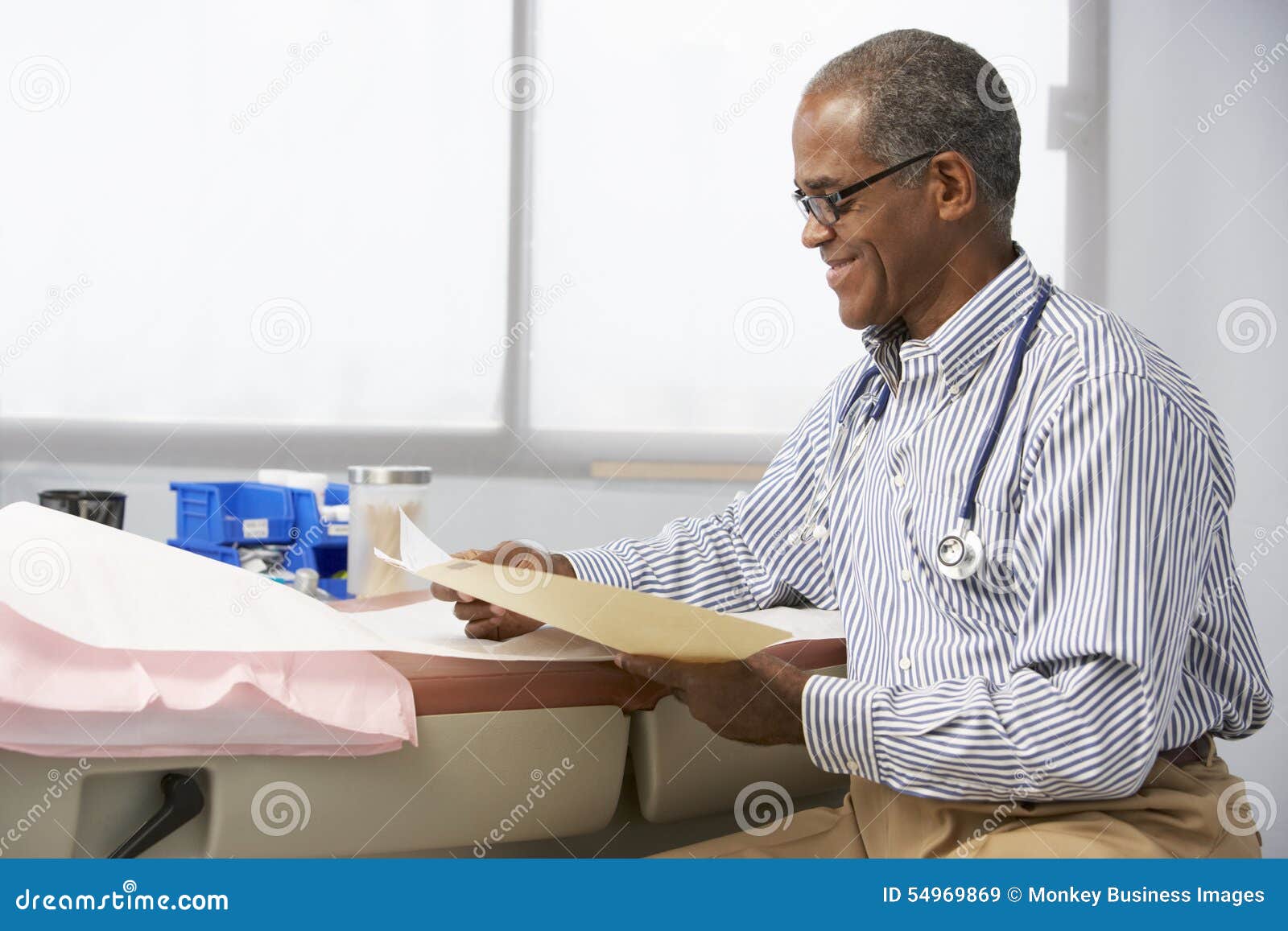 Male Doctor in Surgery Reading Patient Notes Stock Image - Image of ...