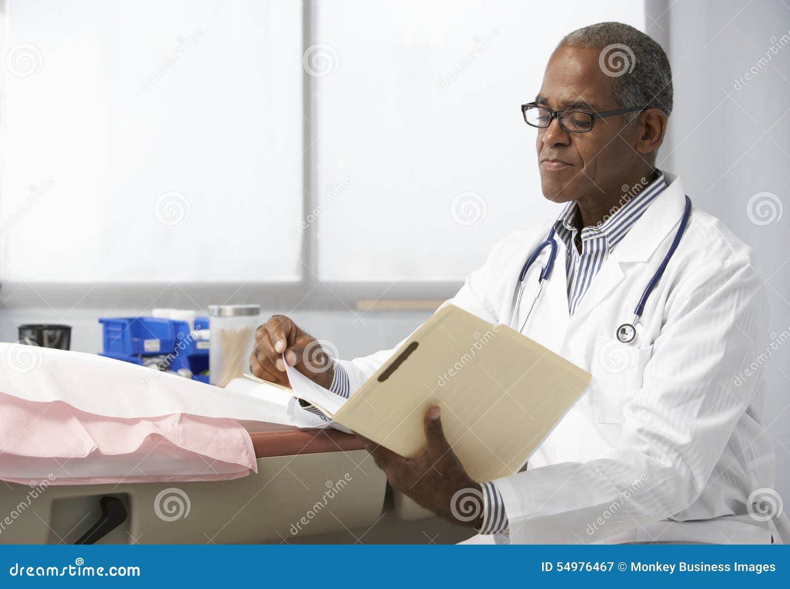 Male Doctor in Surgery Reading Patient Notes Stock Image - Image of ...