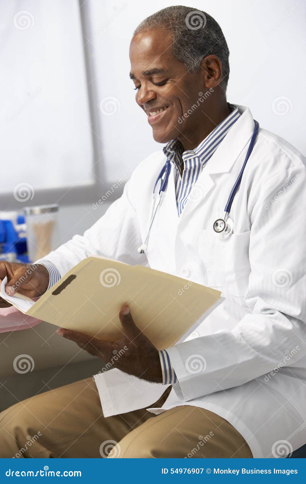 Male Doctor in Surgery Reading Patient Notes Stock Image - Image of ...