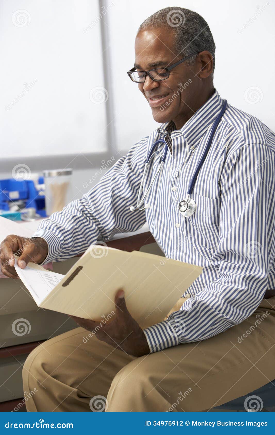 Male Doctor in Surgery Reading Patient Notes Stock Photo - Image of ...