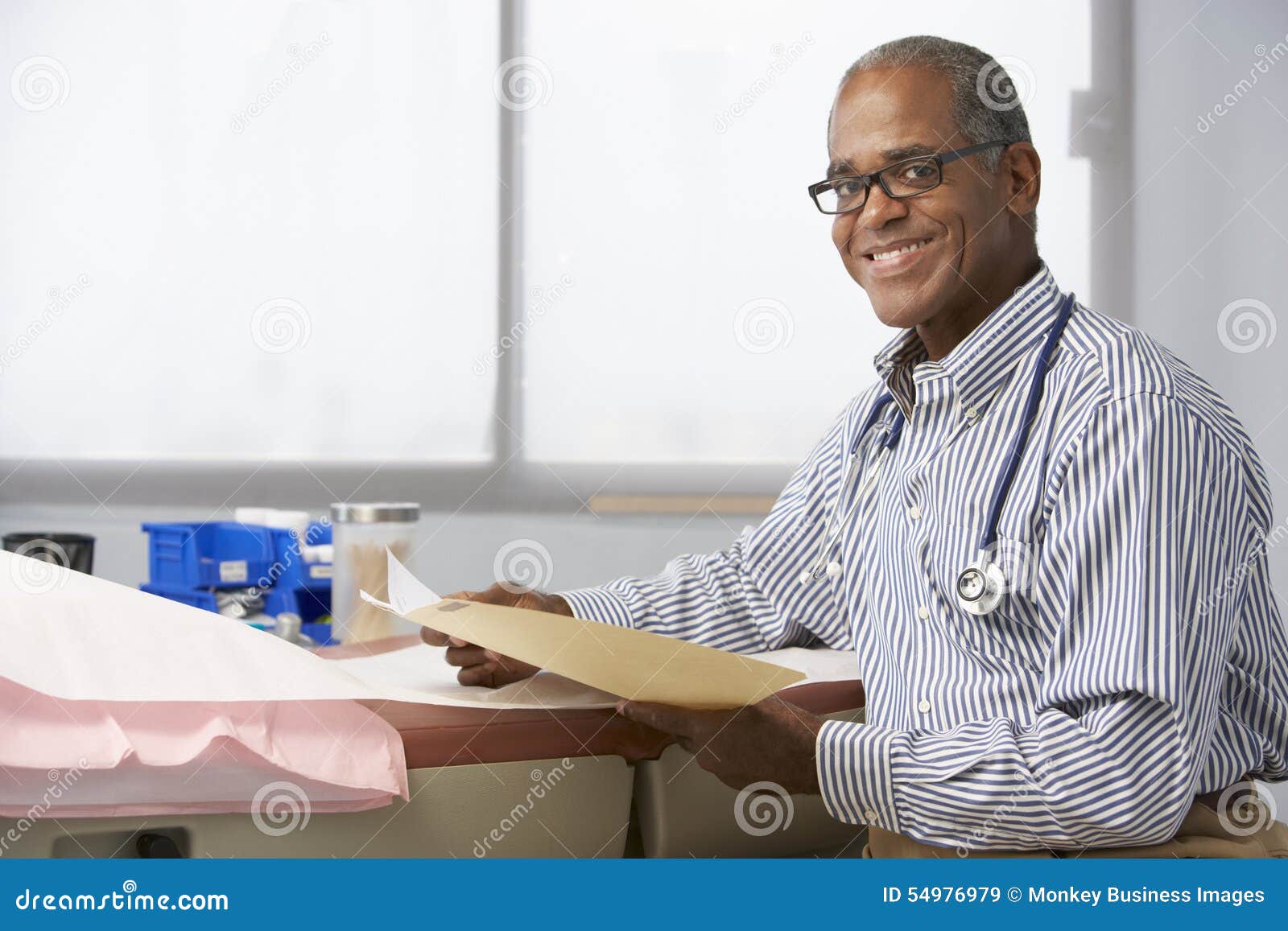 Male Doctor in Surgery Reading Patient Notes Stock Image - Image of ...