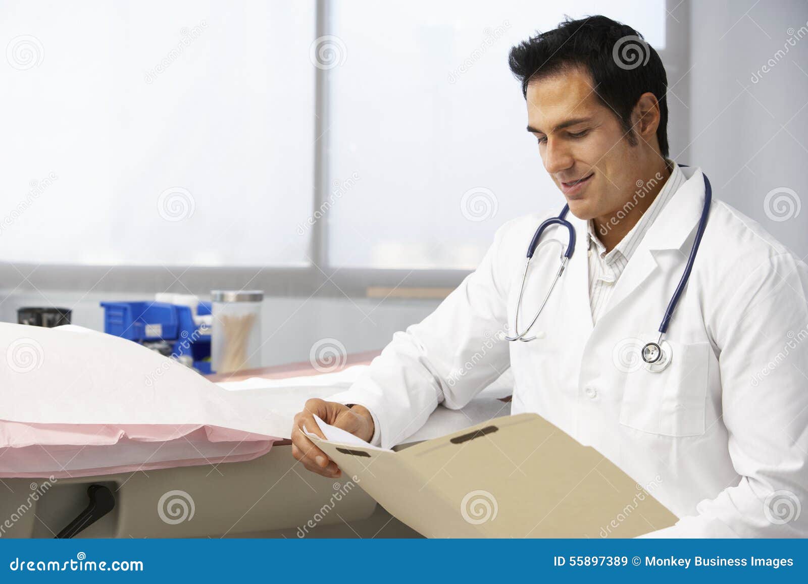 Male Doctor in Surgery Reading Patient Notes Stock Image - Image of ...