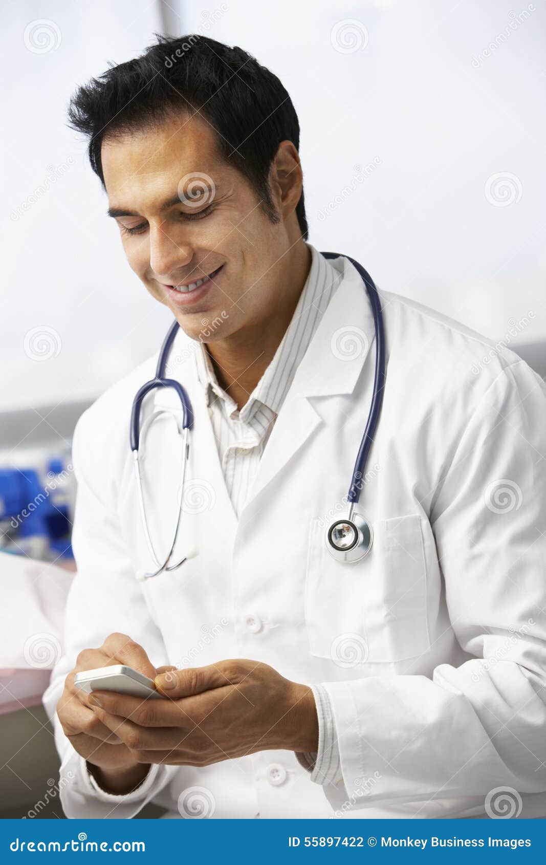 Male Doctor in Surgery Using Mobile Phone Stock Photo - Image of coat ...