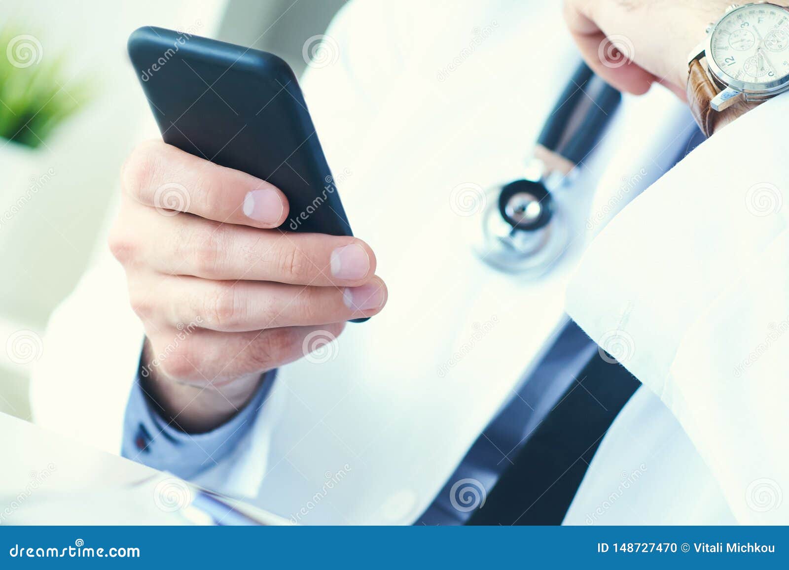 Male Doctor in White Coat is Using a Modern Smartphone Device with ...