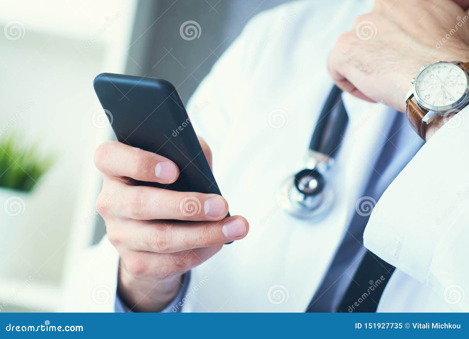 Male Doctor in White Coat is Using a Modern Smartphone Device with ...