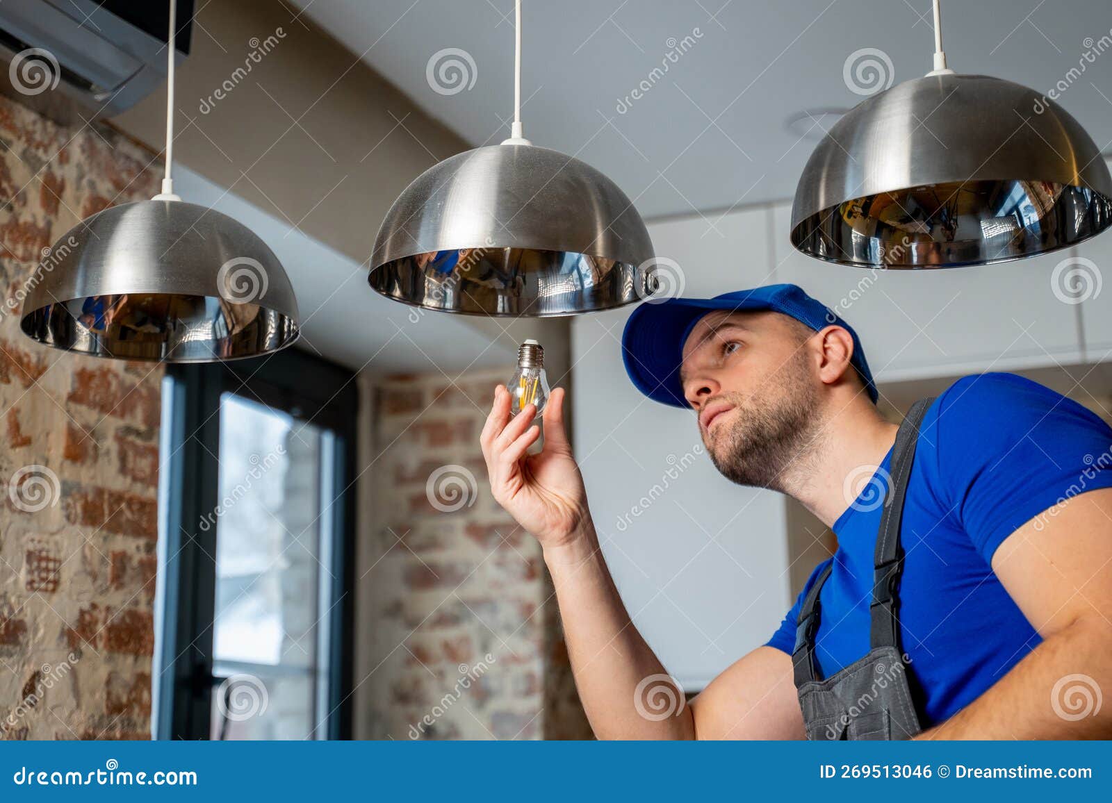 Male Electrician Changes the Light Bulbs in the Lamp. a Young Man in ...