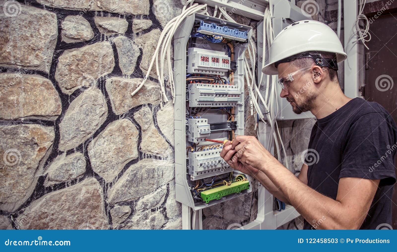 A Male Electrician Works in a Switchboard with an Electrical Con Stock ...