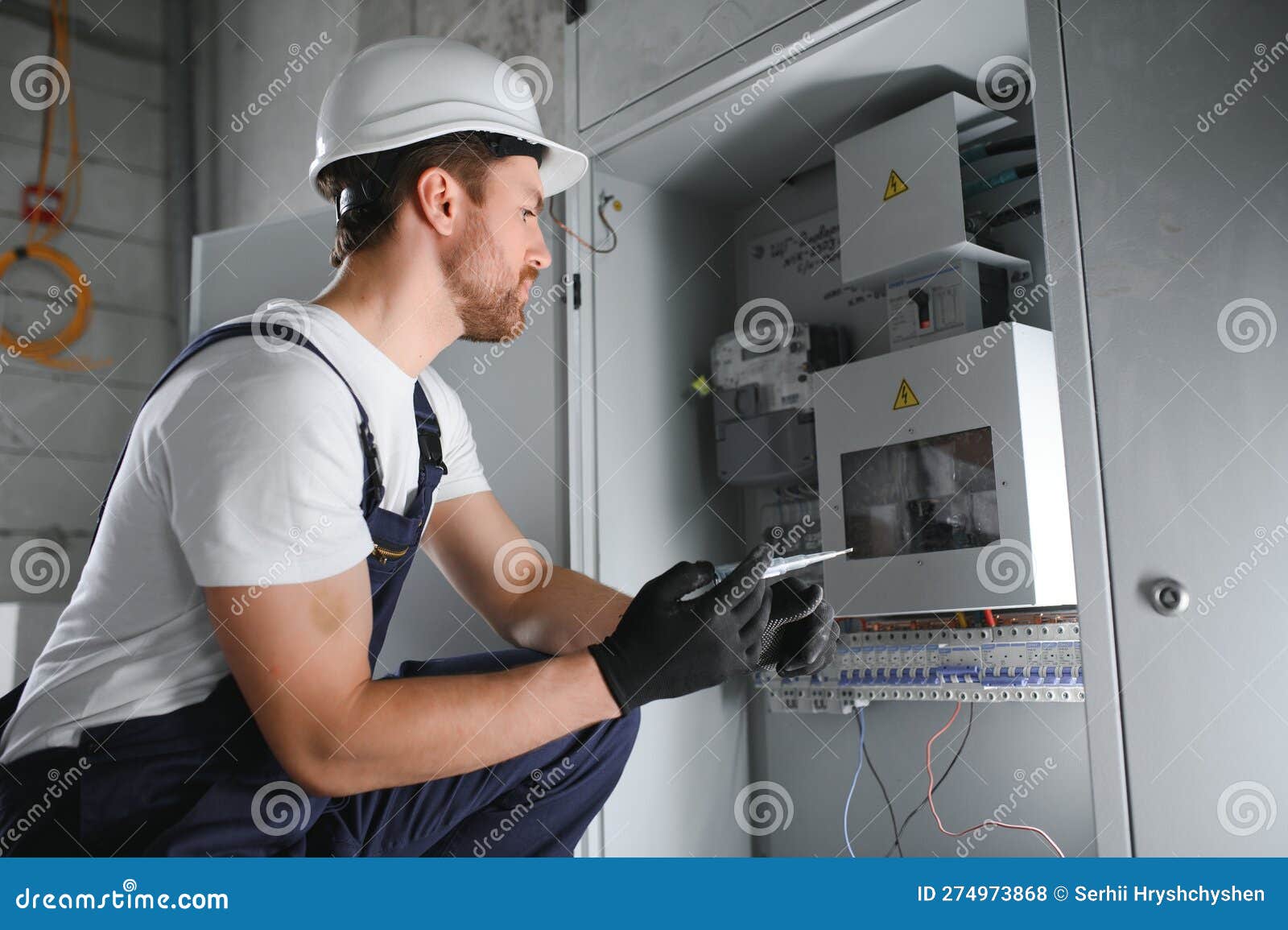 A Male Electrician Works in a Switchboard with an Electrical Connecting ...