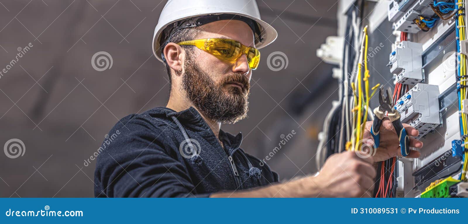 A Male Electrician Works in a Switchboard with an Electrical Connecting ...