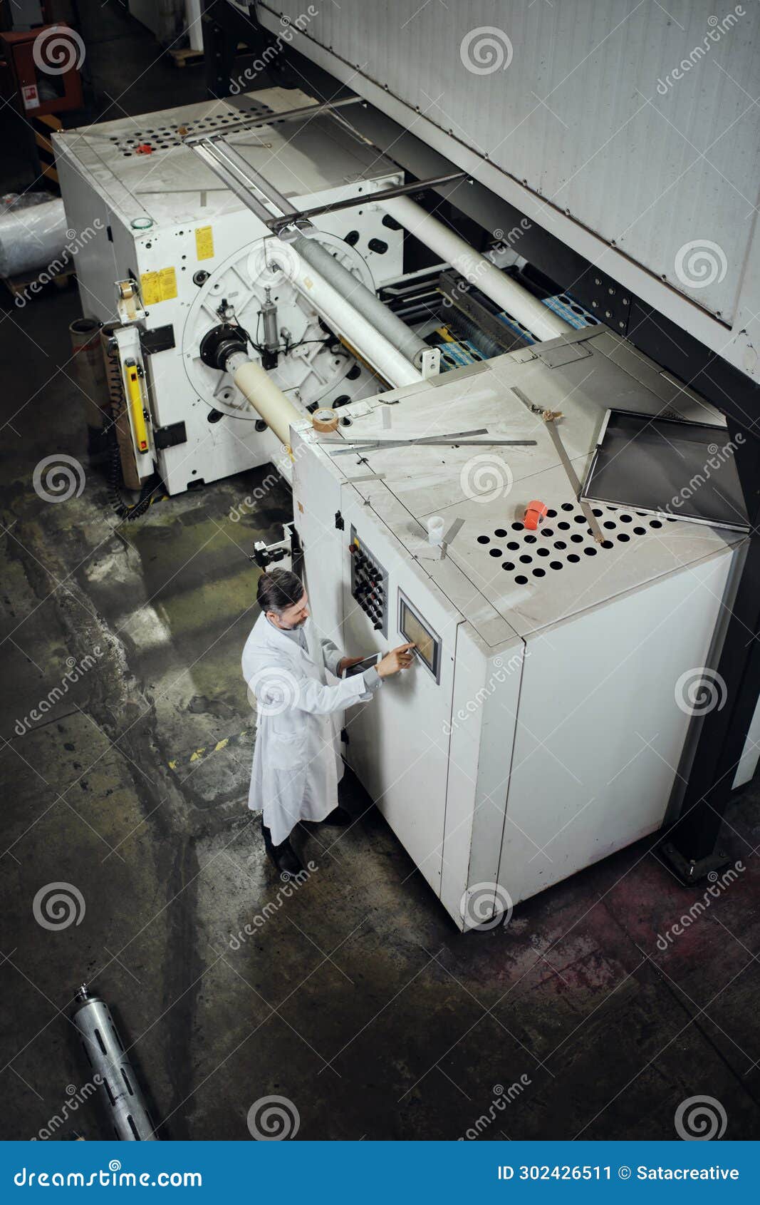 Engineer Working at the Factory Surrounded with Machinery, Checking ...