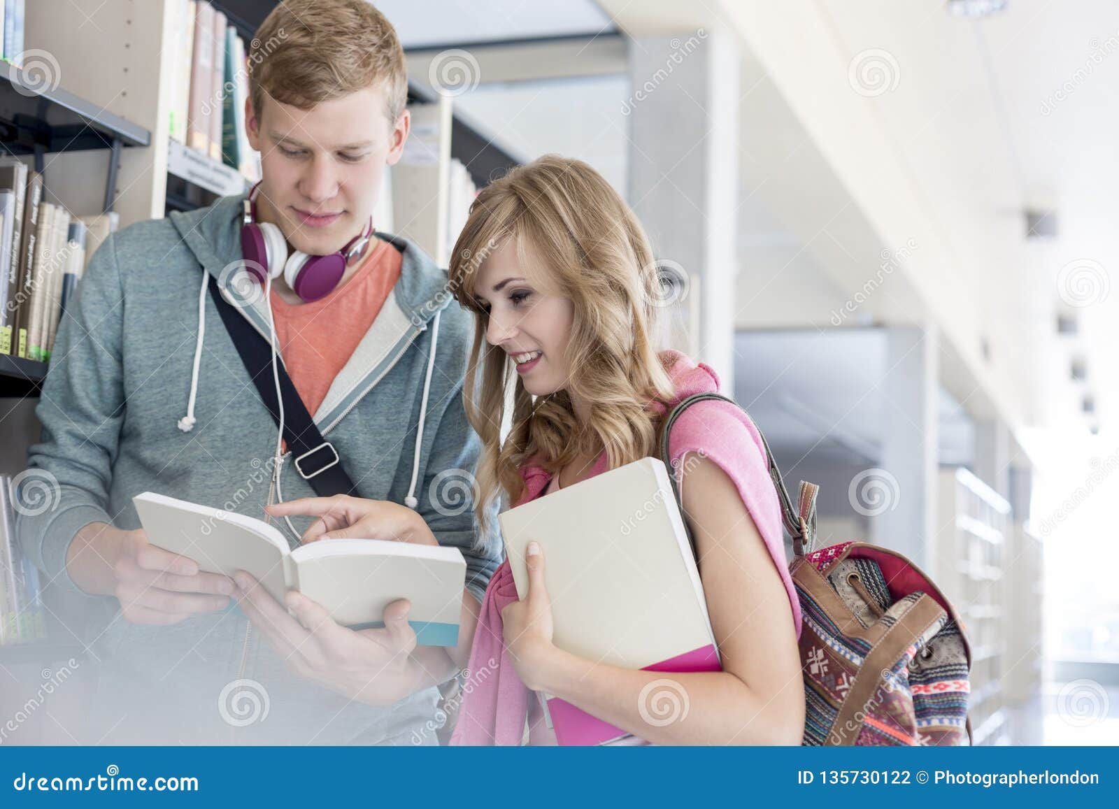 Male and Female Students Discussing Over Books by Shelf at University ... Male and Female Students Discussing Over Books by Shelf at University ...