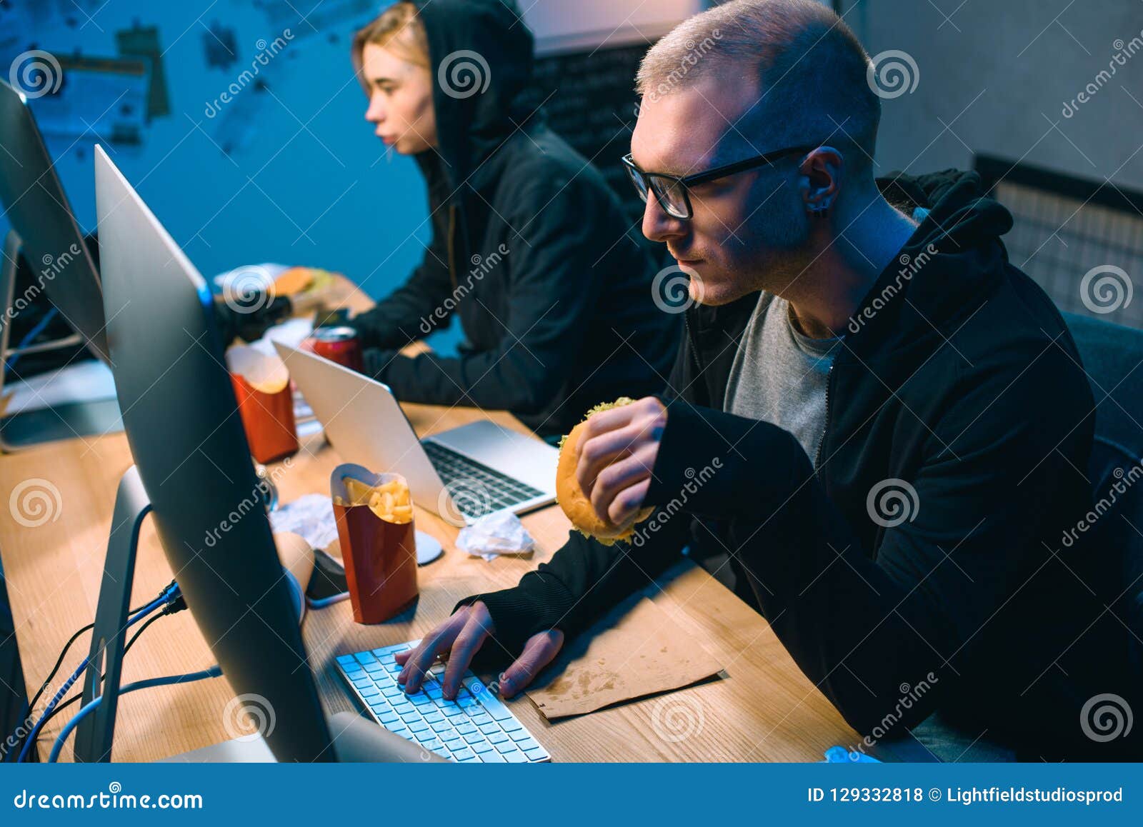 Male Hacker Working on Malware with Accomplice and Eating Stock Photo ...