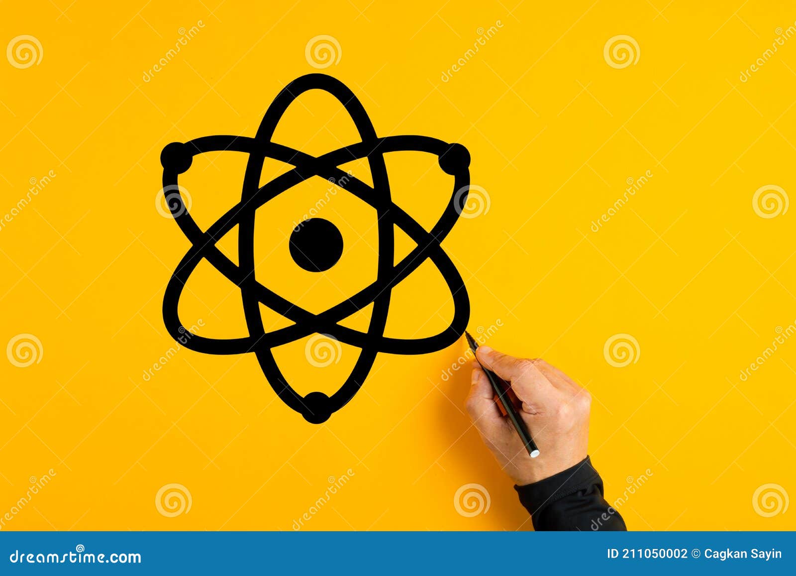 Male Hand Drawing an Atom Icon on Yellow Background. Science and ...