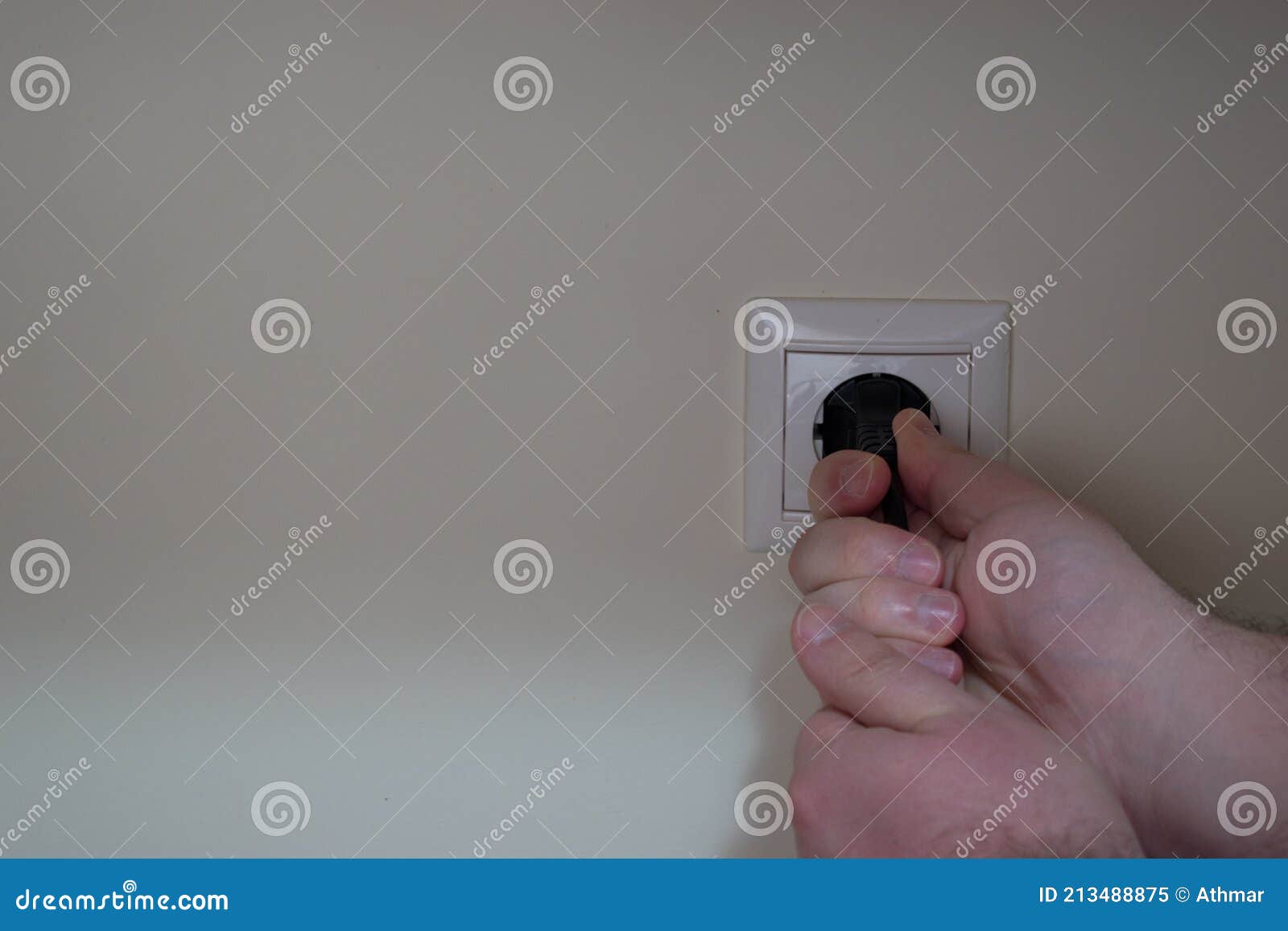 Male Hands are Pulling Out a Black Electrical Cord Plugged into a Wall ...
