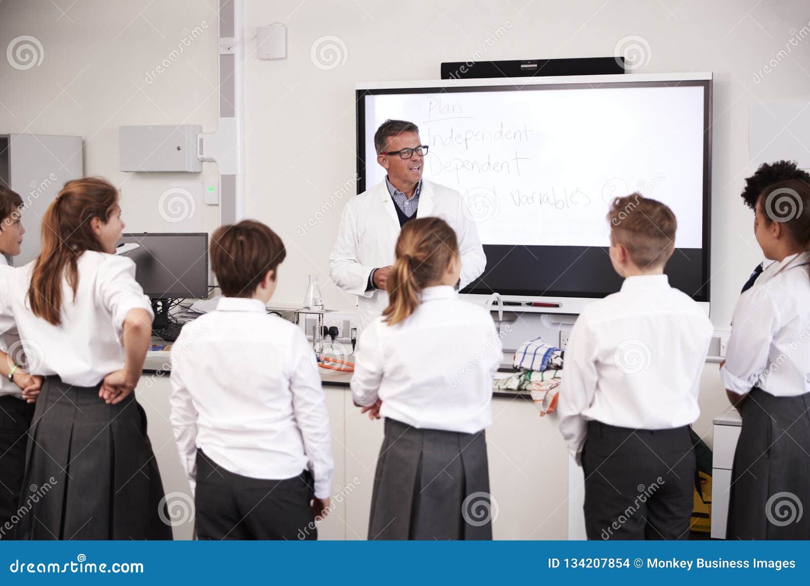 Male High School Tutor Teaching High School Students Wearing Uniforms ...