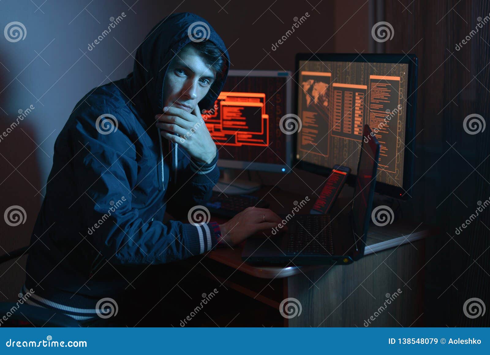 Man In The Hood Looking In The Camera Hacker Attacks And Online Fraud On The Screen Background