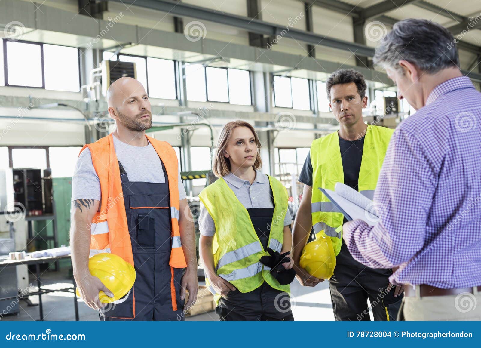 Male Inspector Examining File by Manual Workers in Industry Stock Photo ...