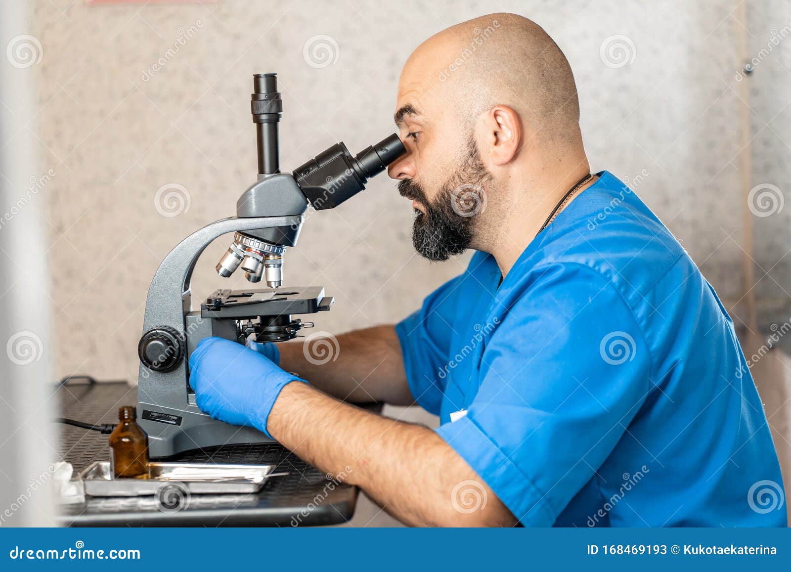 Male Laboratory Assistant Examining Biomaterial Samples in a Microscope ...