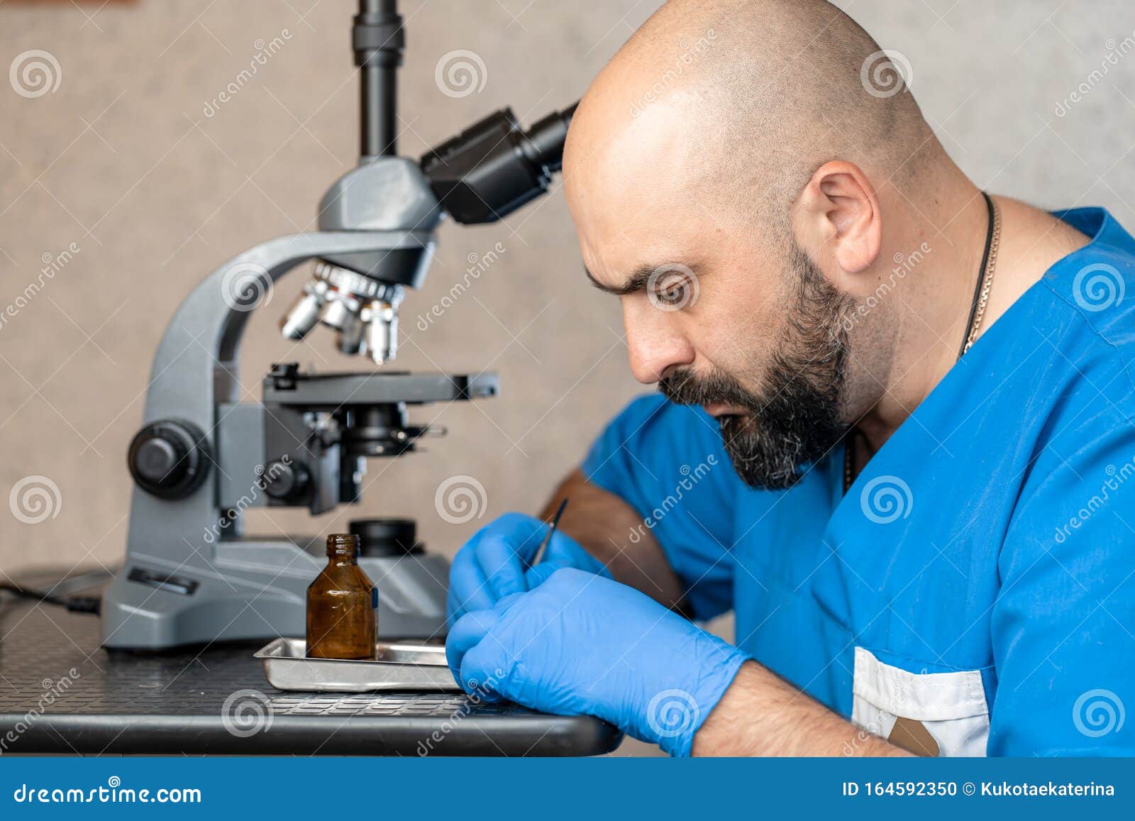 Male Laboratory Assistant Examining Biomaterial Samples in a Microscope ...