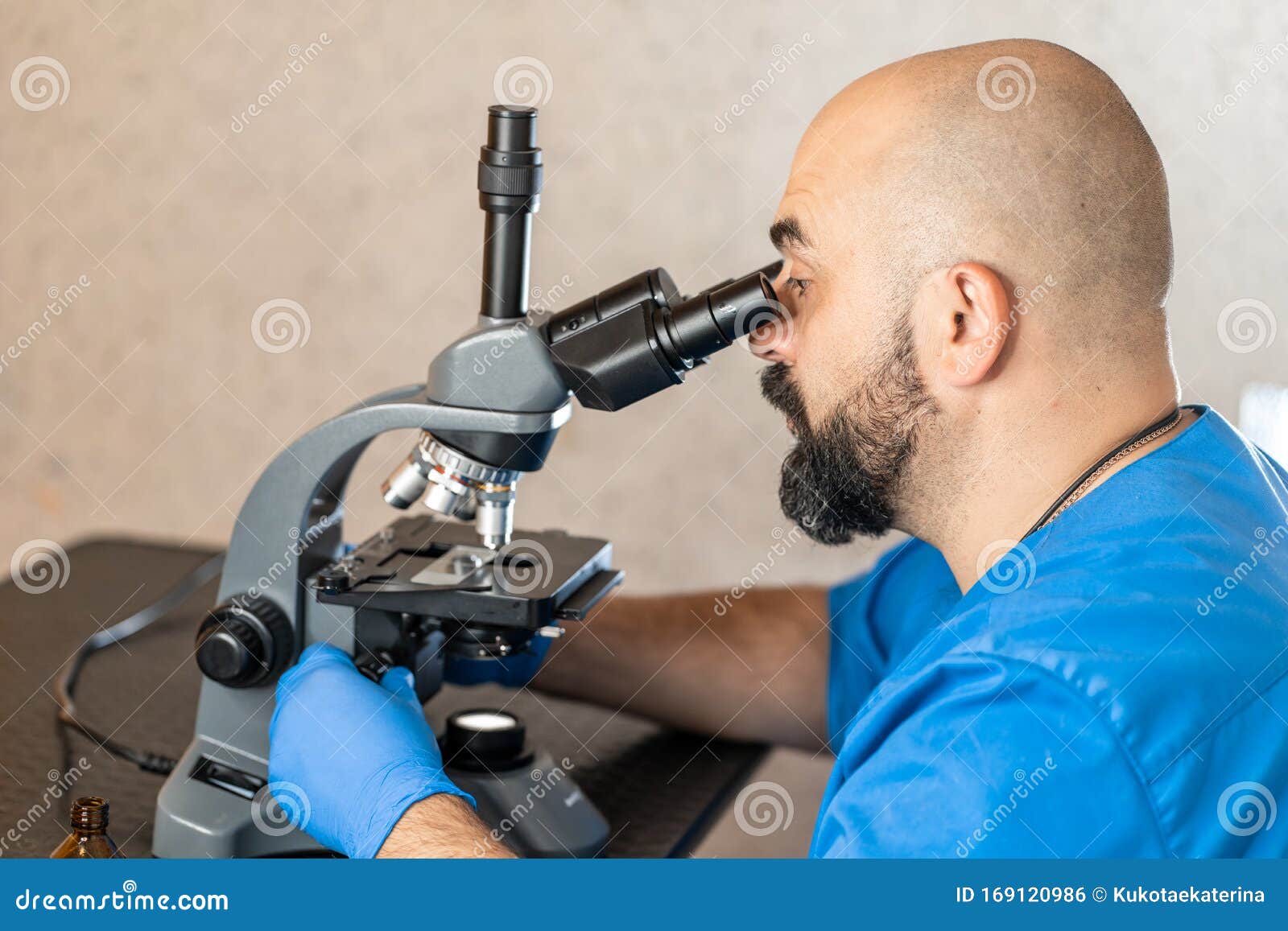 Male Laboratory Assistant Examining Biomaterial Samples in a Microscope ...