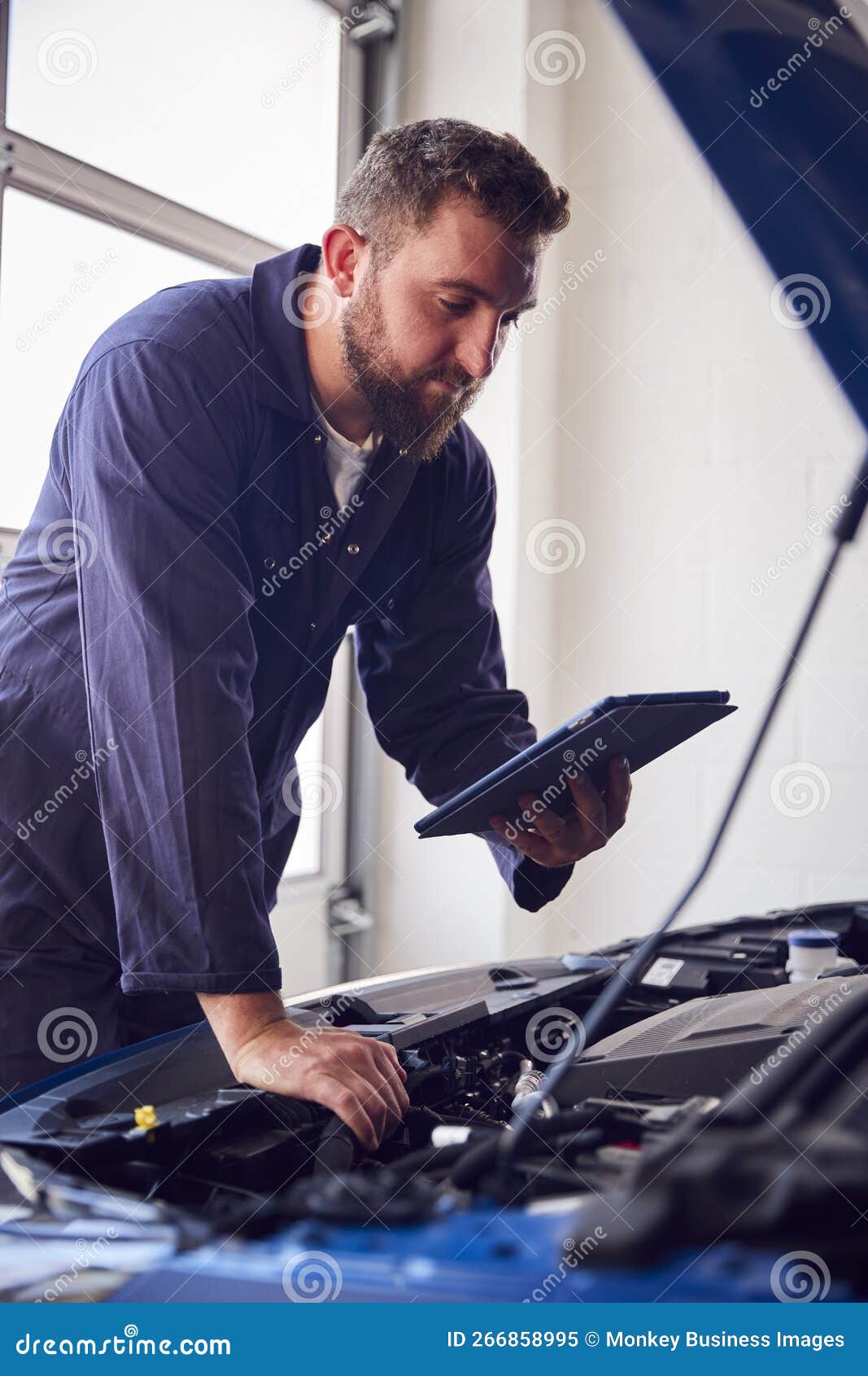 Male Mechanic in Garage Using Diagnostic Software on Digital Tablet To ...