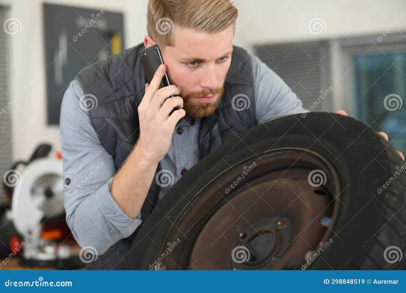 Male Mechanic Looking at Wheel and Talking on Smartphone Stock Image ...