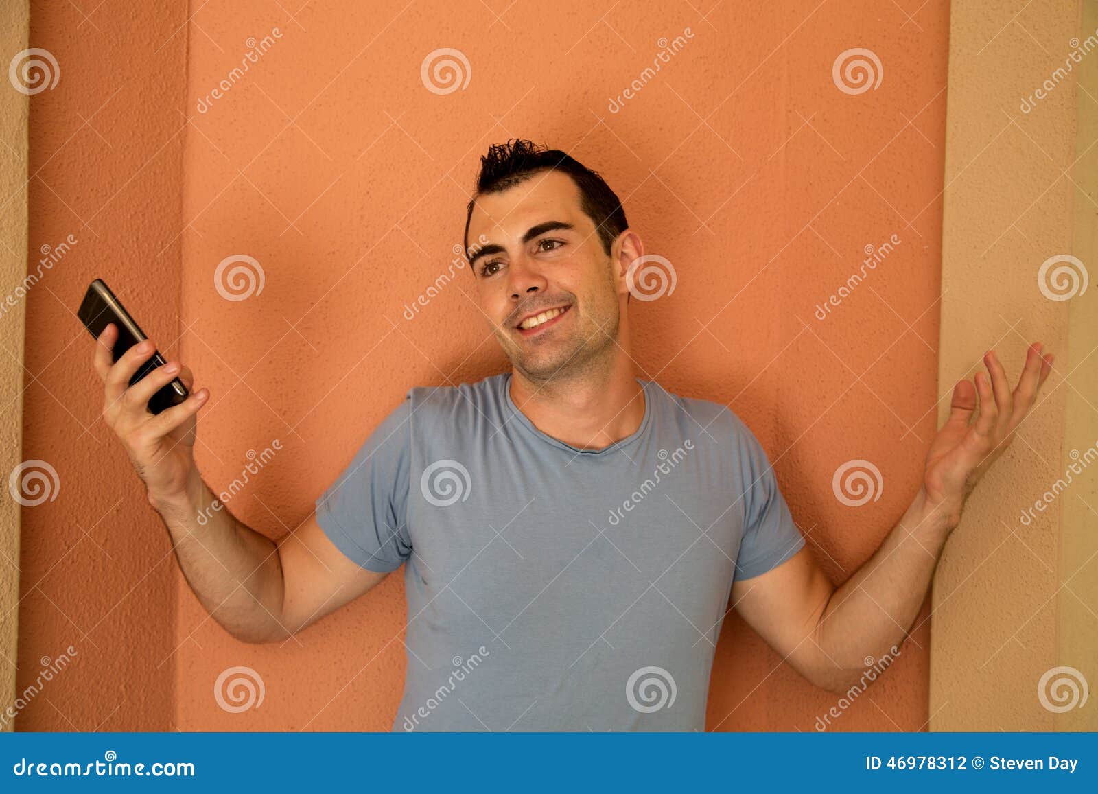 Male Model with Cell Phone in Hand Showing a Whatever Attitude Stock ...