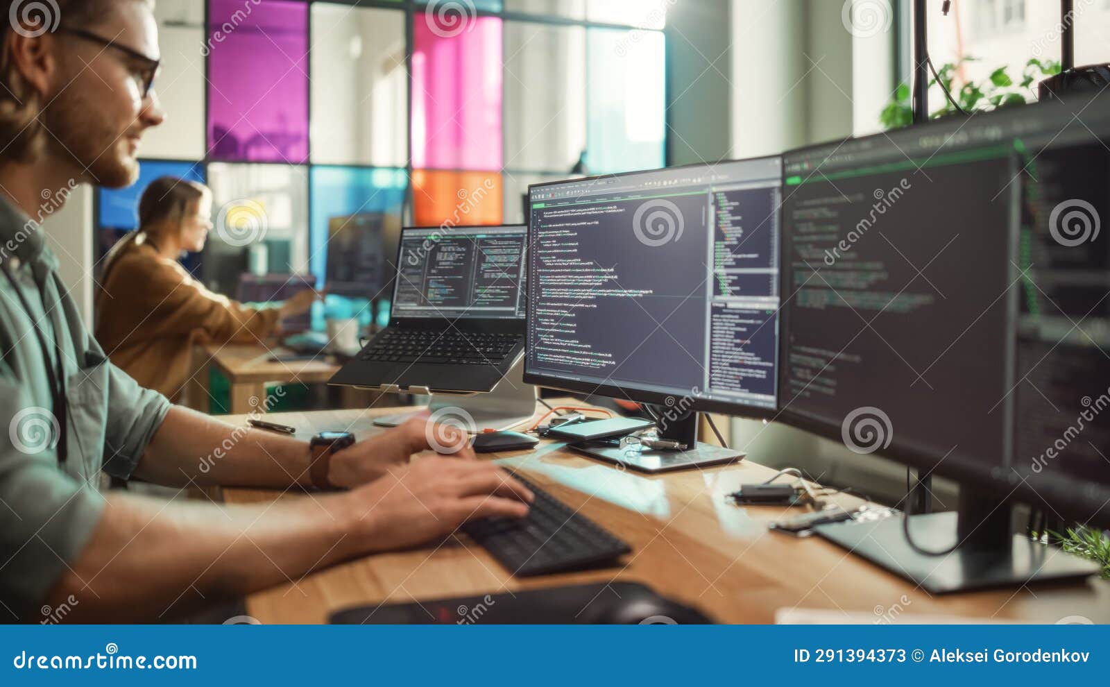 Male Programmer Coding On Desktop Computer With Two Monitors Set Up In 9739