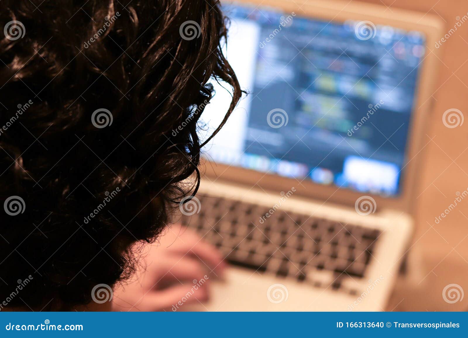 Male Programmer Working On Laptop Computer At Desk In Office Blurry
