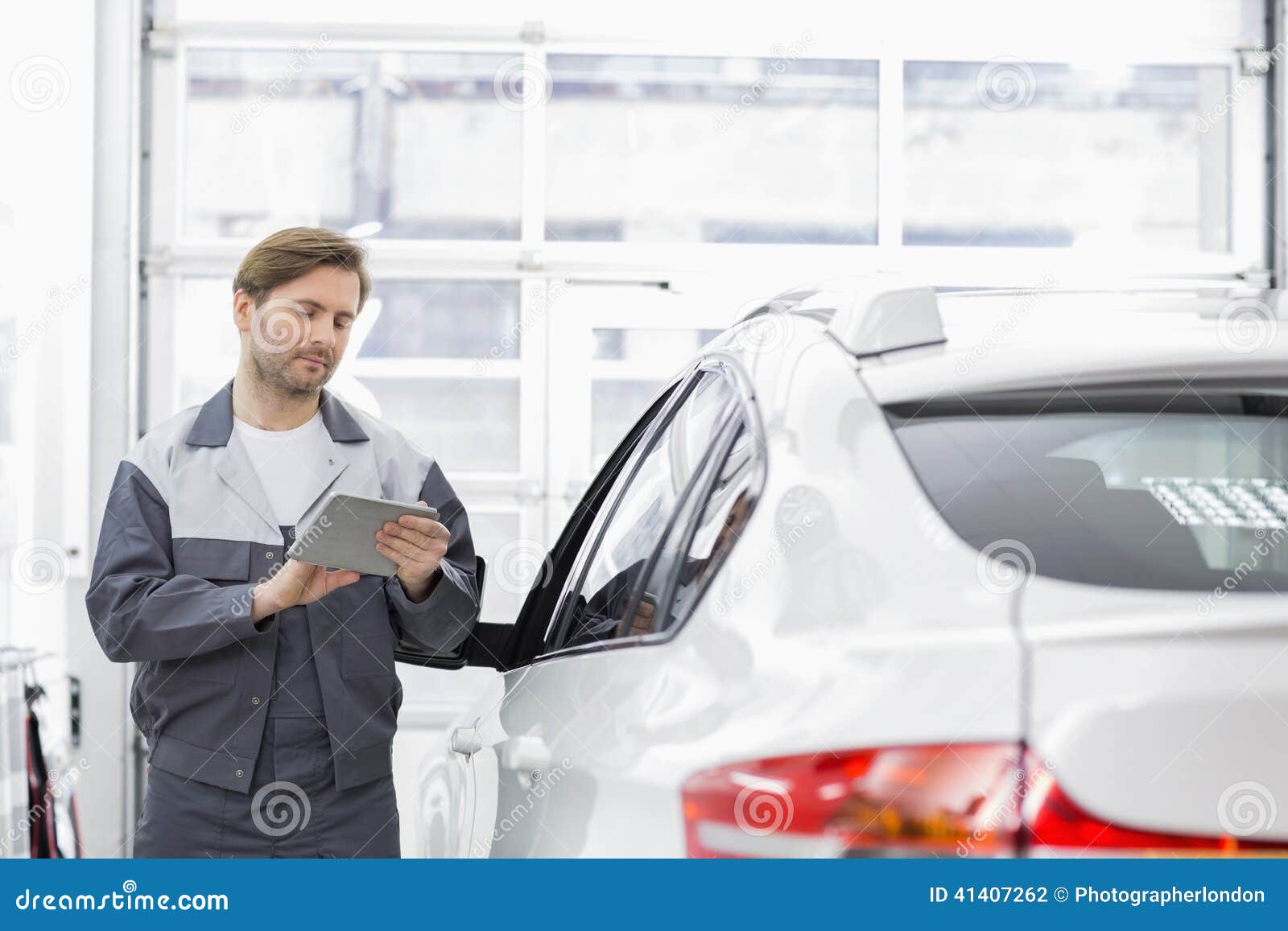 Male Repair Worker Using Tablet PC while Standing by Car in Workshop ...