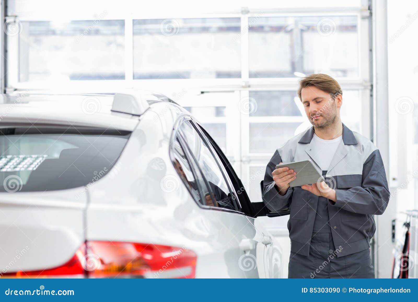 Male Repair Worker Using Tablet PC while Standing by Car in Workshop ...