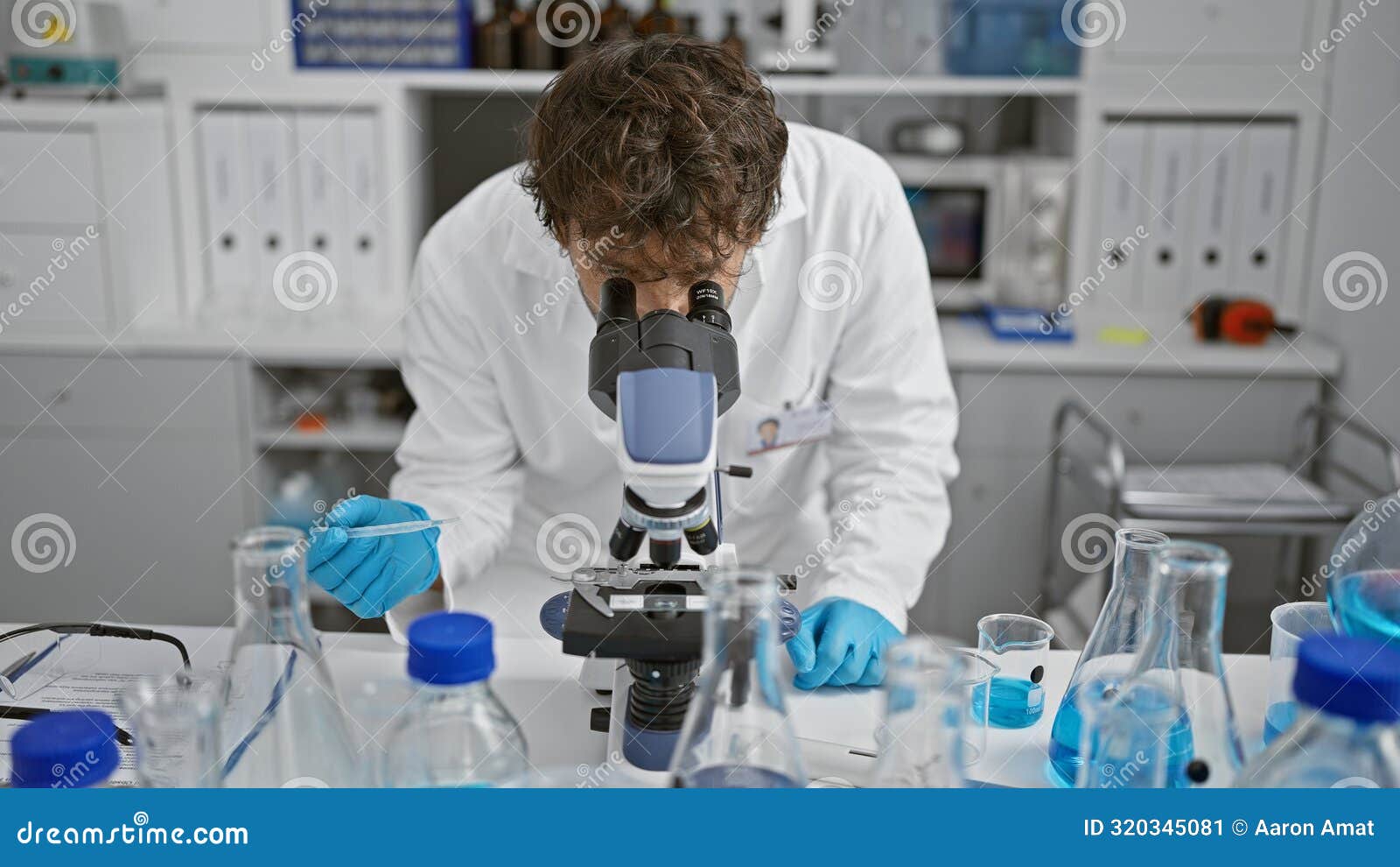 A Male Scientist Analyzes Samples Using a Microscope in an Indoor ...