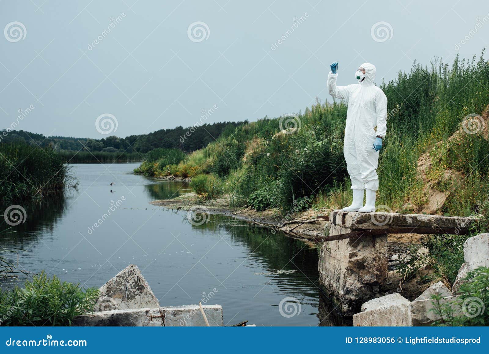 Male Scientist in Protective Mask and Suit Looking at Sample of Water ...