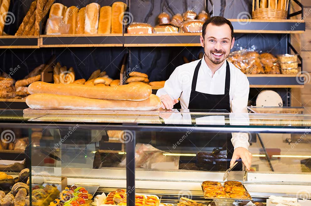 Male Shop Assistant Demonstrating Fresh Delicious Pastry In Bake Stock