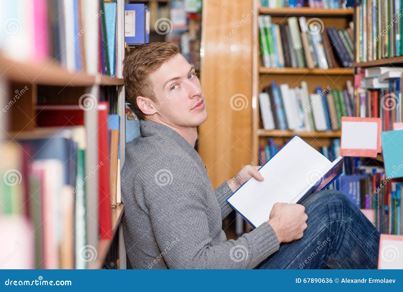 Male Student with Book Sitting on Floor in Library Stock Photo - Image ...