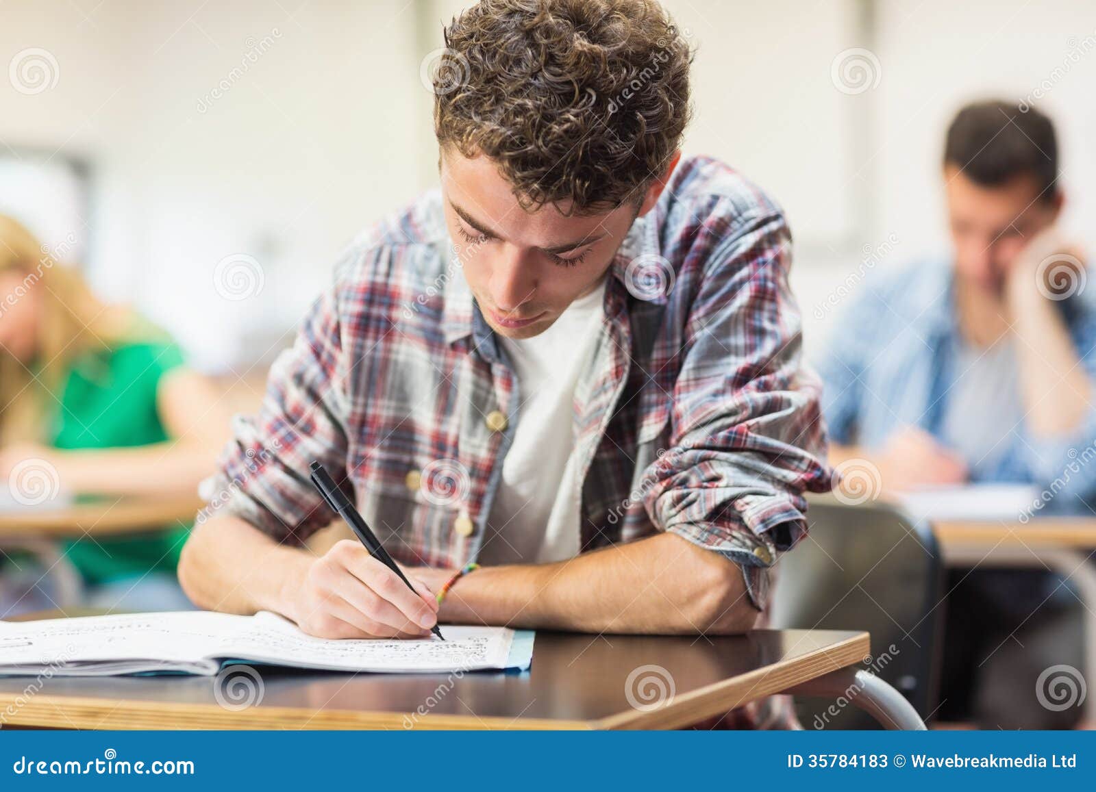 Male Student with Others Writing Notes in Classroom Stock Image - Image ...