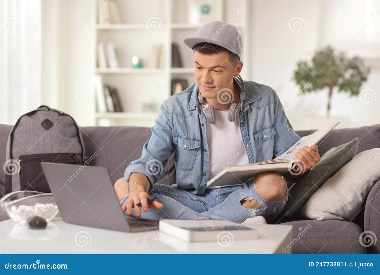 Male Student Studying at Home with a Book and a Laptop Computer Stock ...
