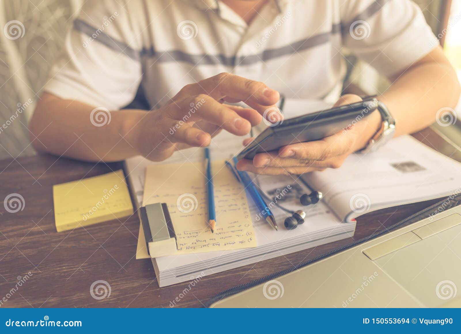 Male Student Using Cellphone while Studying with Workbook on Table ...