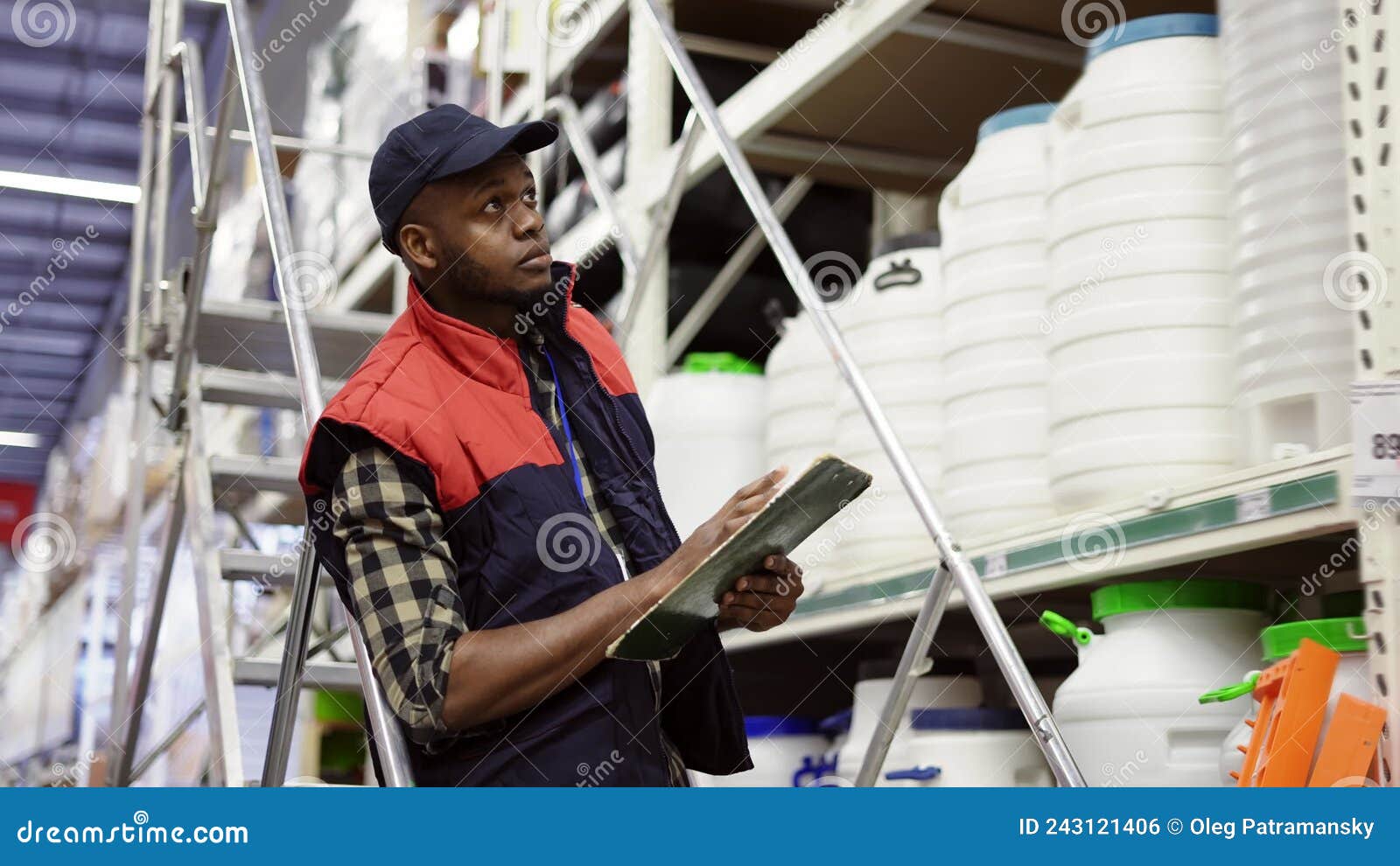 Male Supervisor Examining Goods on Shelves with Tablet Using Ladder ...