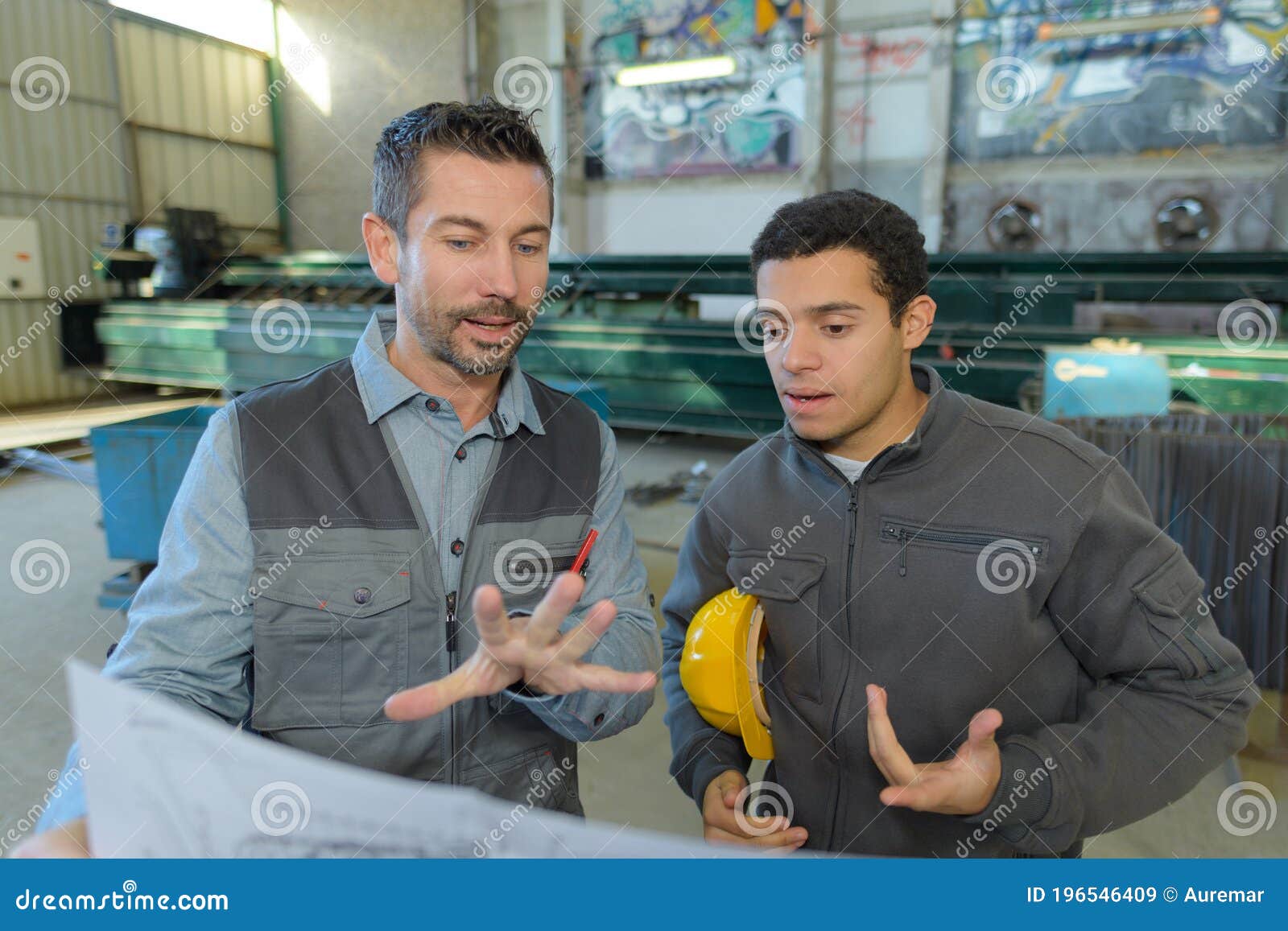 Male Supervisor with Workers Discussing Over Blueprints in Industry ...