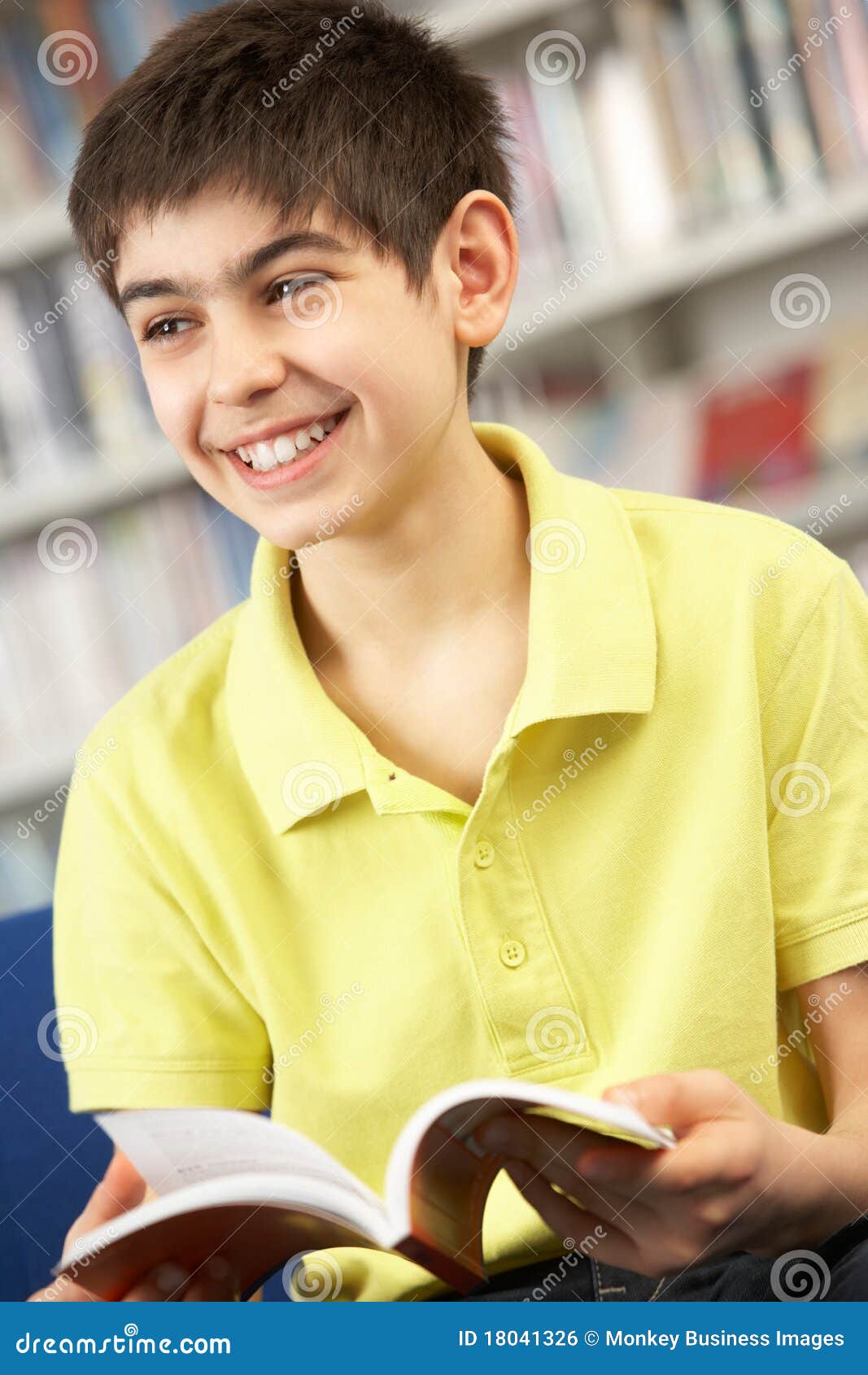 Male Teenage Student in Library Reading Book Stock Photo - Image of ...