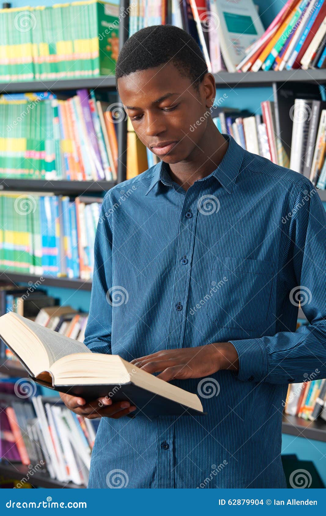 Male Teenage Student Reading Book in Library Stock Photo - Image of ...