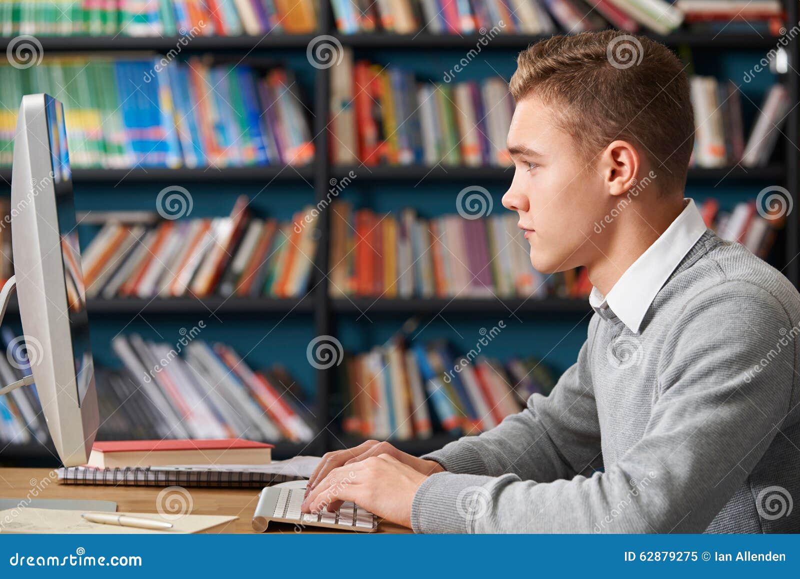 Male Teenage Student Working at Computer in Library Stock Image - Image ...