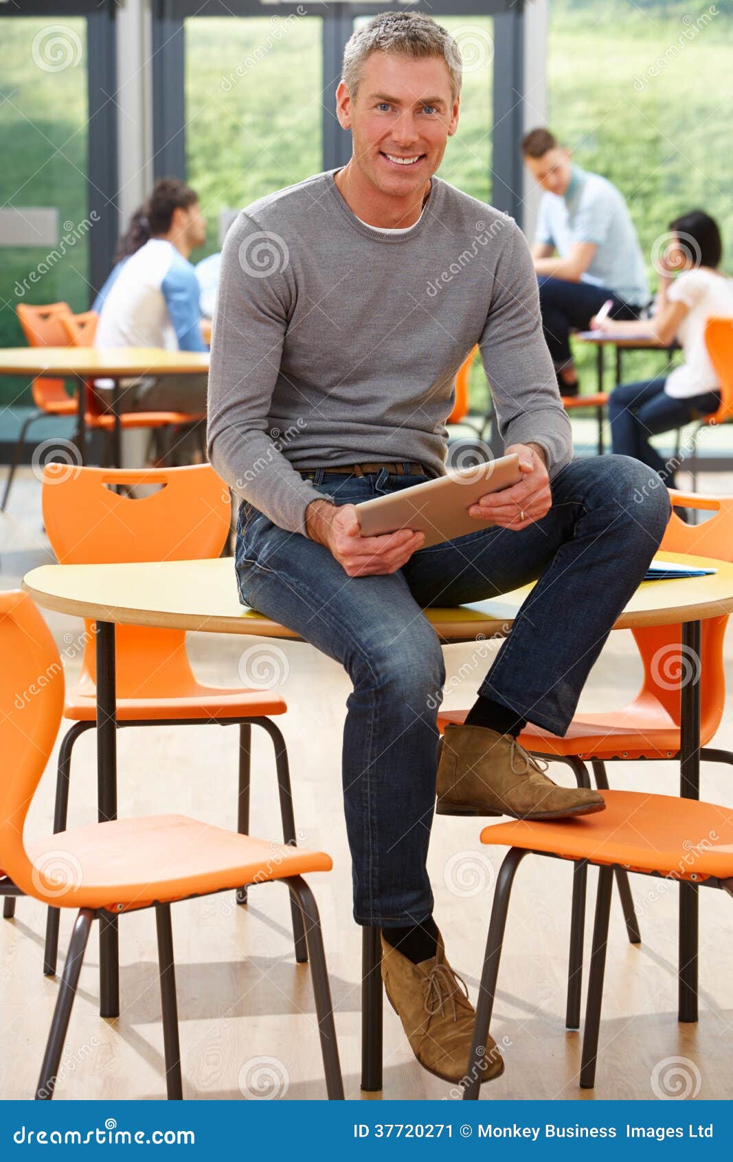 Male Tutor Sitting in Classroom with Digital Tablet Stock Image - Image ...
